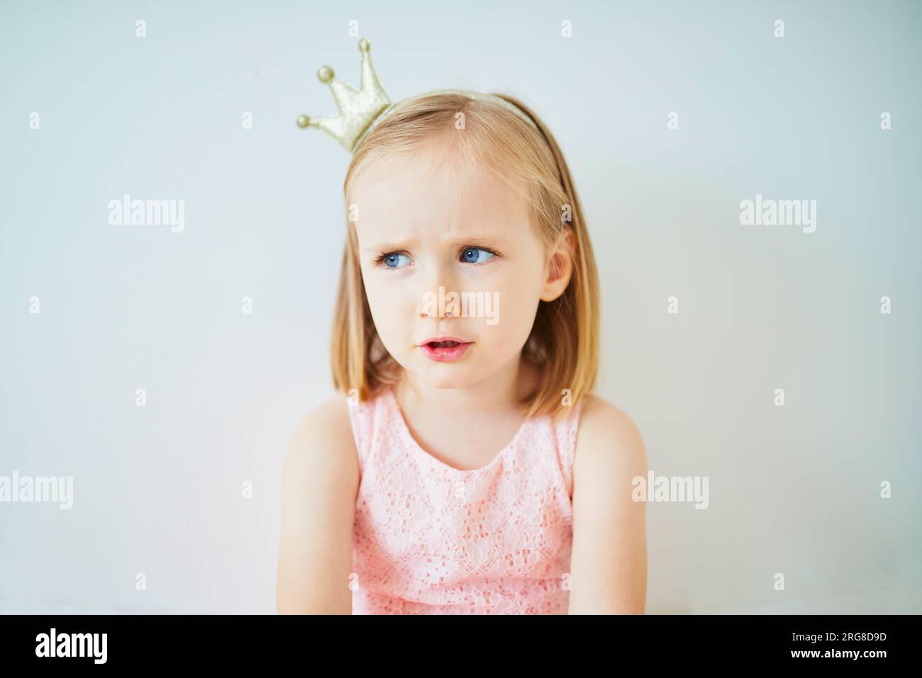 Adorable little girl in pink dress and golden crown dressed as princess ...