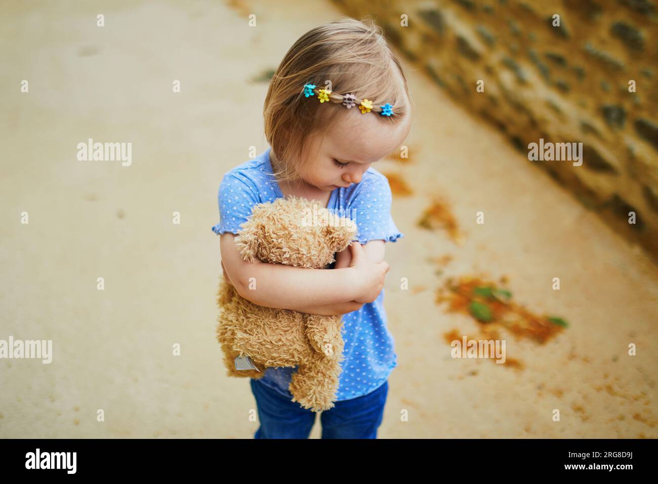 Unhappy and emotional toddler girl with teddy bear outdoors ...