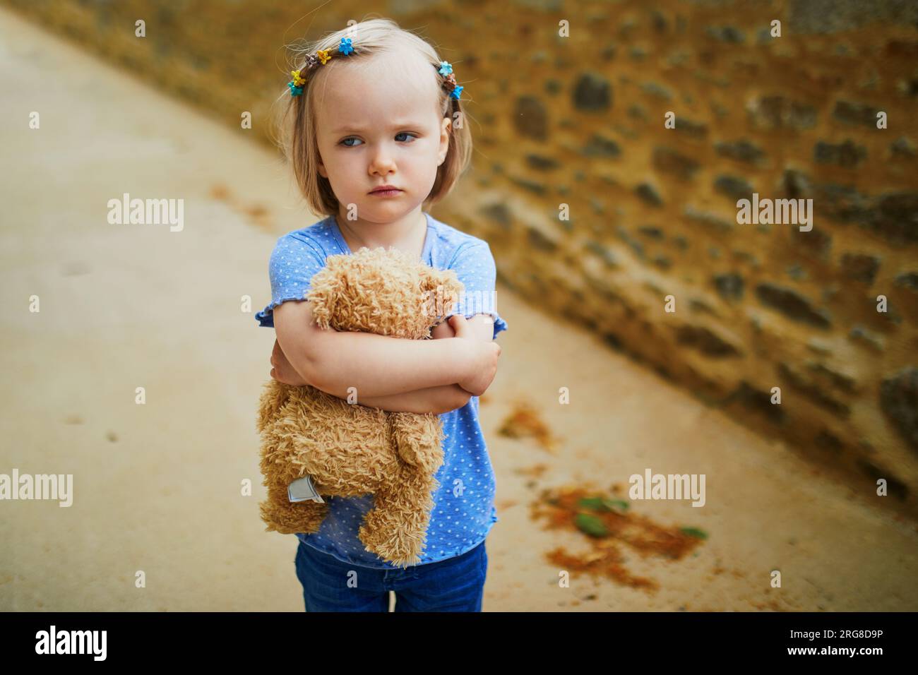 Unhappy and emotional toddler girl with teddy bear outdoors ...