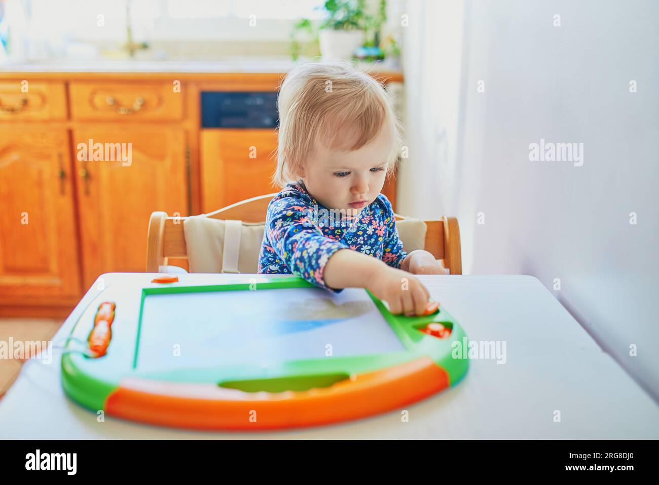 Adorable little girl drawing on magnetic magic screen at home, in ...