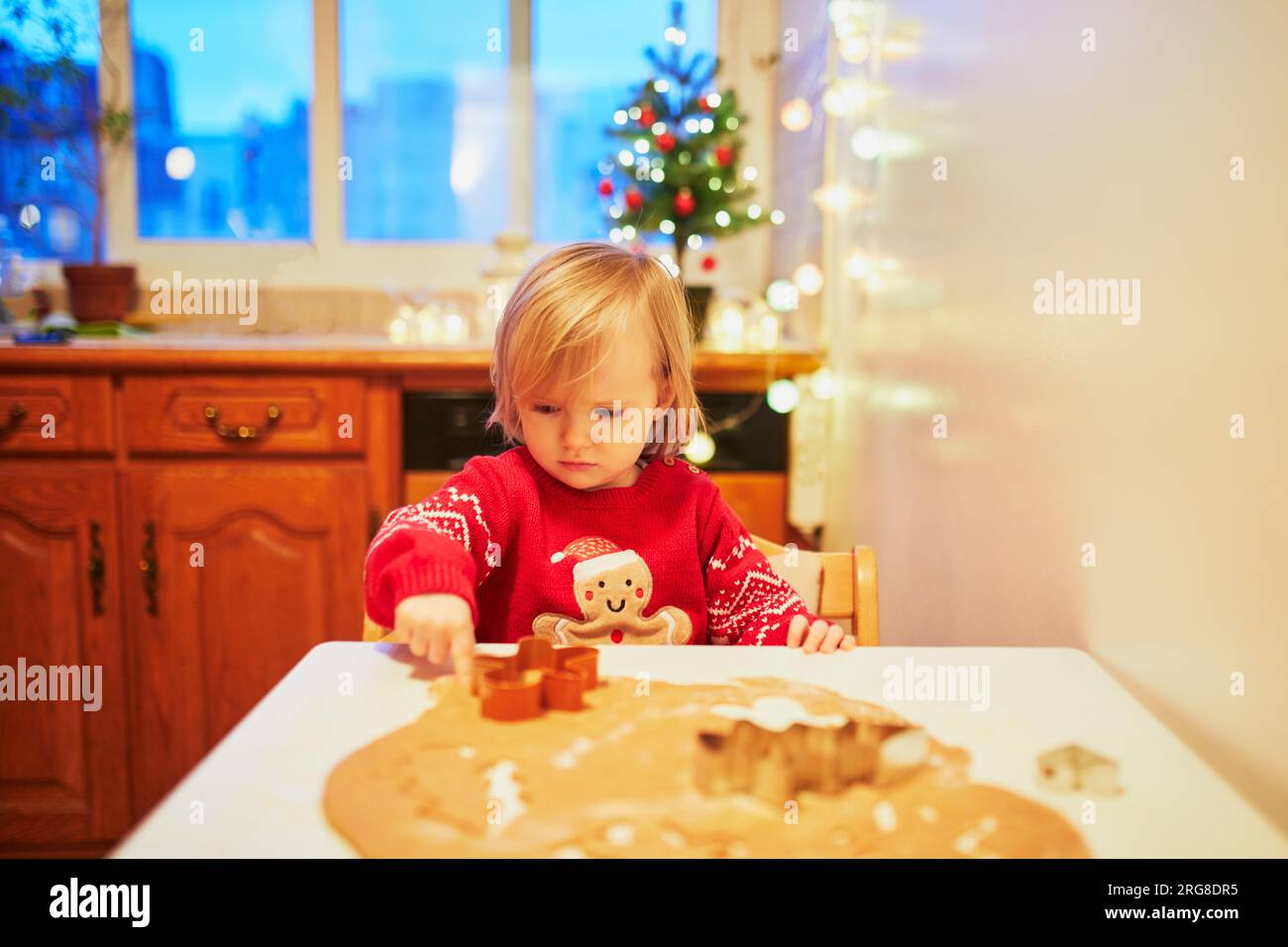 Adorable little toddler girl cooking Christmas cookies. Celebrating ...