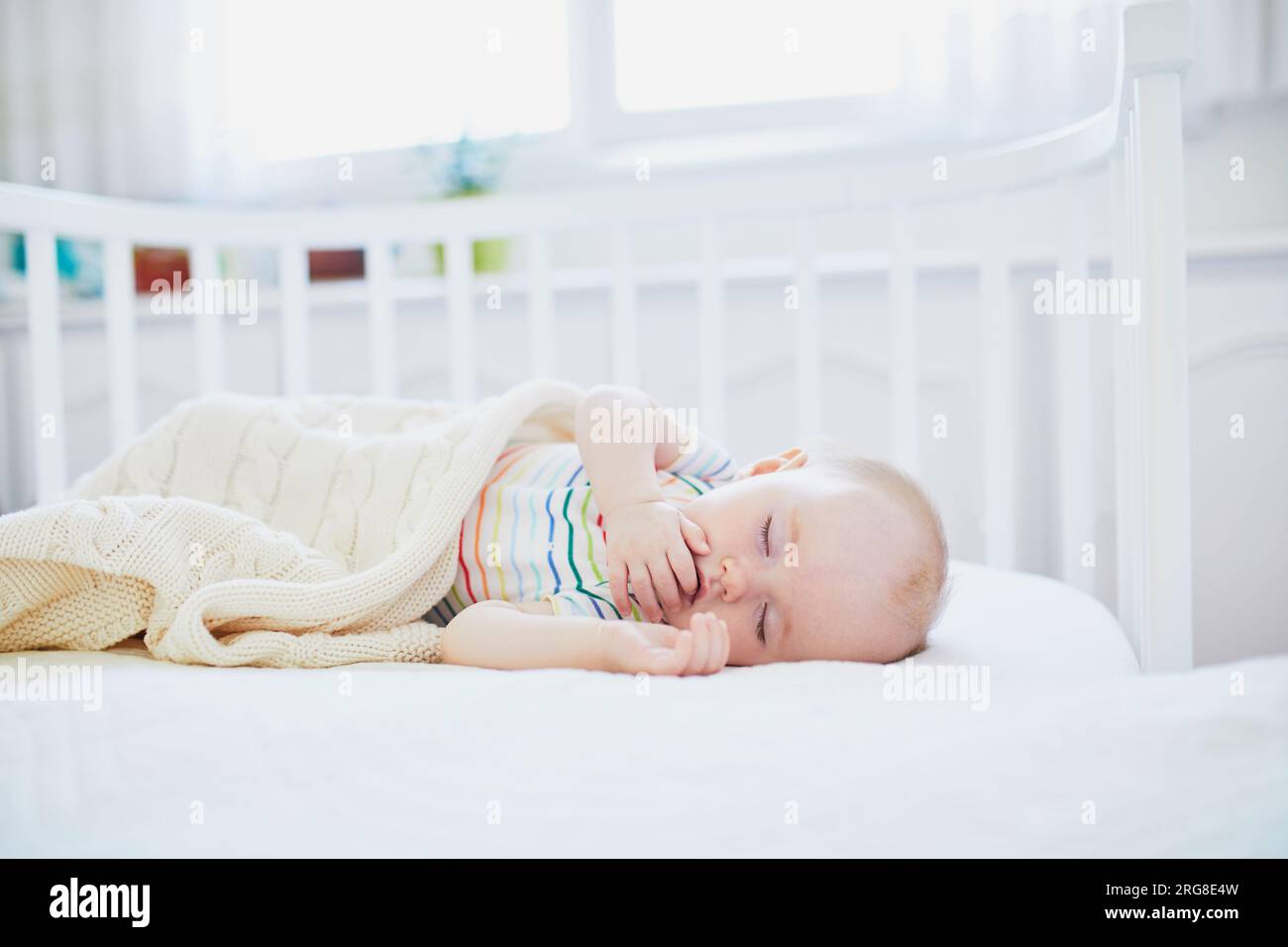Adorable baby girl sleeping in co-sleeper crib attached to parents' bed ...