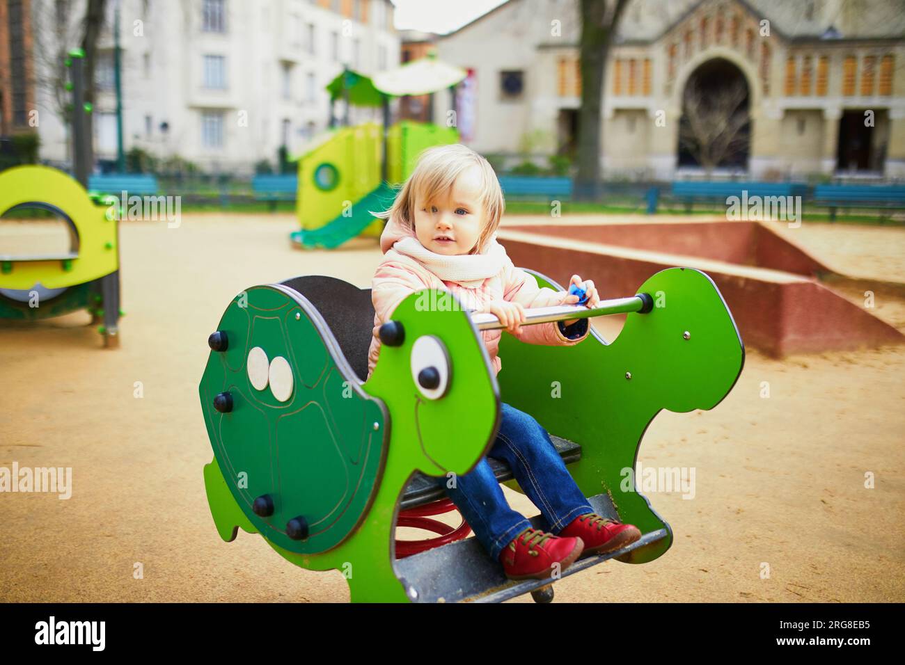 Adorable toddler girl having fun on spring rider on playground. Outdoor ...