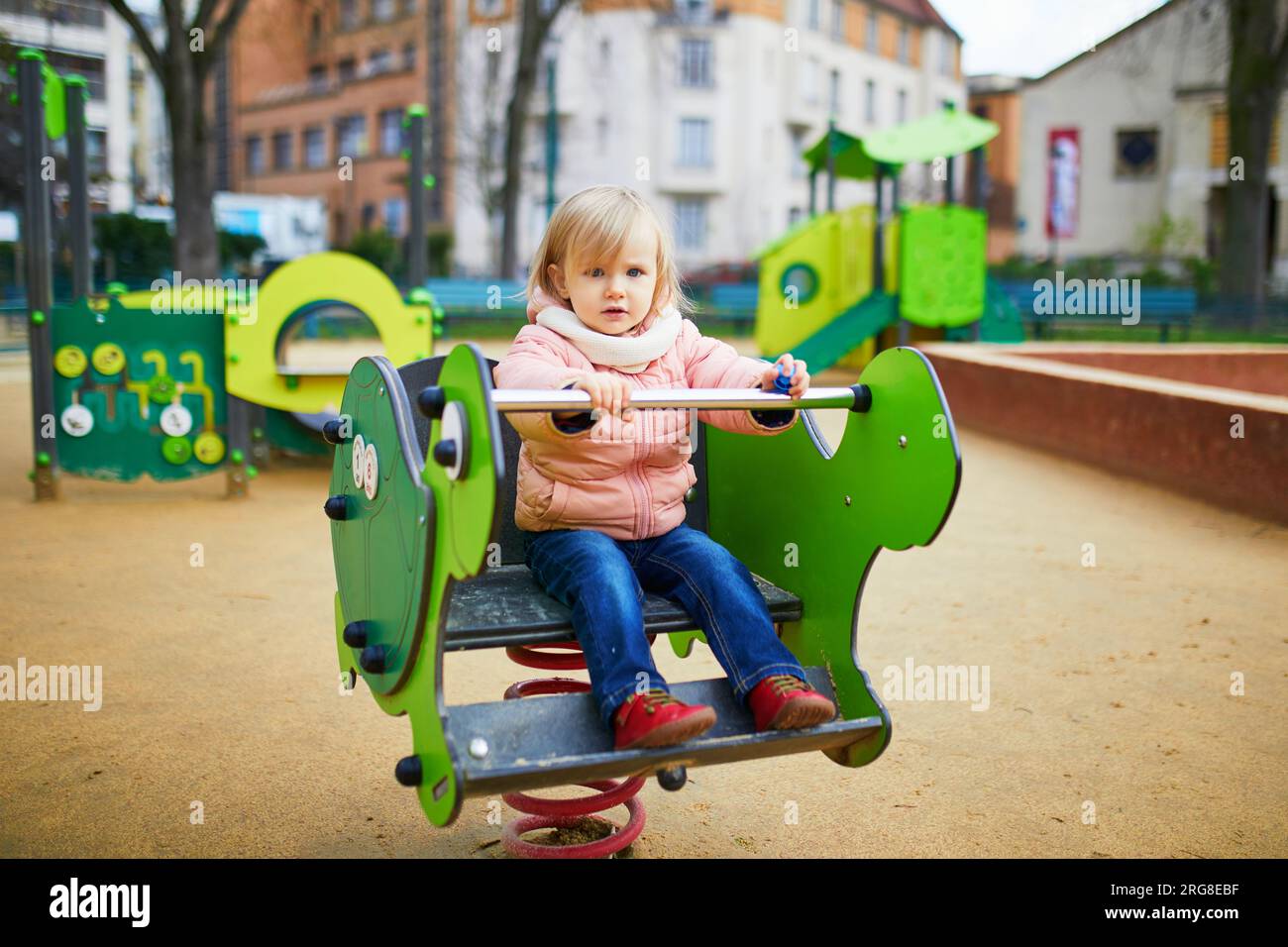 Adorable toddler girl having fun on spring rider on playground. Outdoor ...