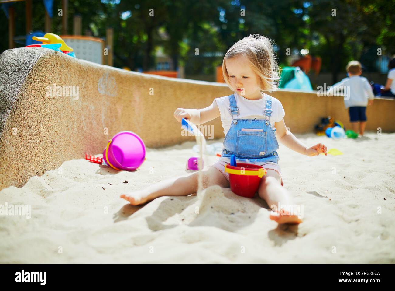 Adorable little girl having fun on playground in sandpit. Toddler ...
