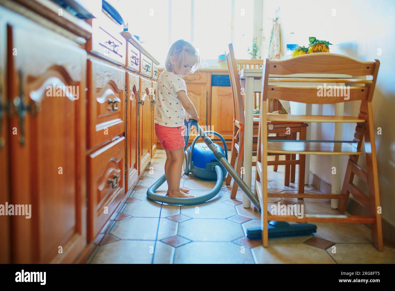Adorable toddler girl using vacuum cleaner at home. Child helping ...