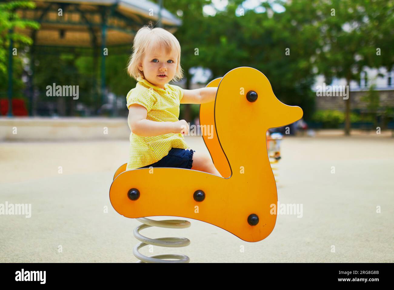 Adorable toddler girl having fun on spring rider on playground. Outdoor ...
