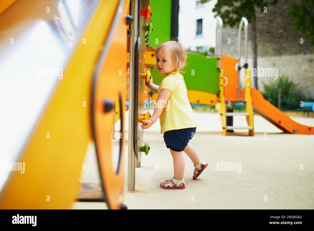 Adorable toddler girl on playground near slide. Child playing on the ...