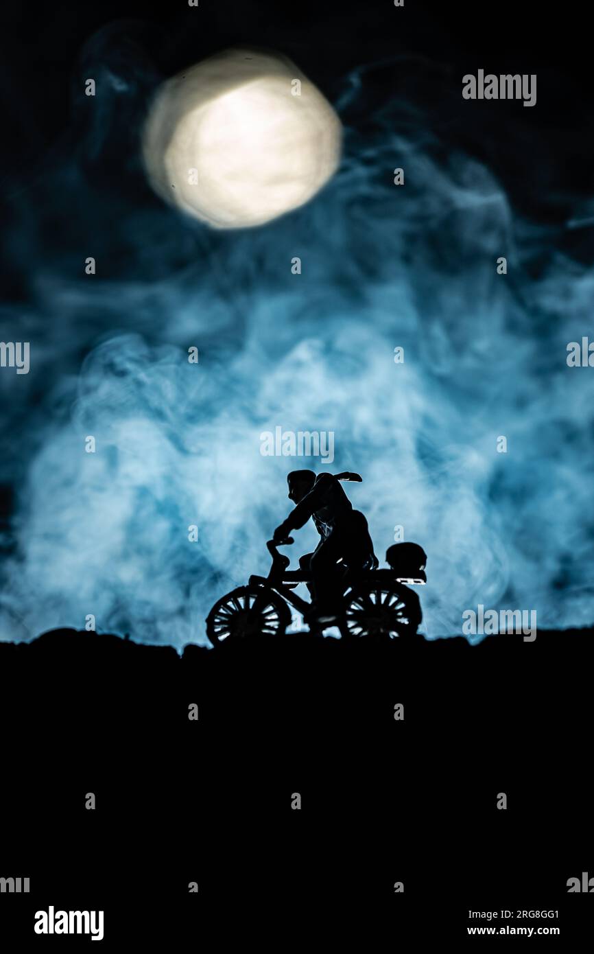 Moonlight bicycle ride Miniature cyclist figurine travels down a rural ...