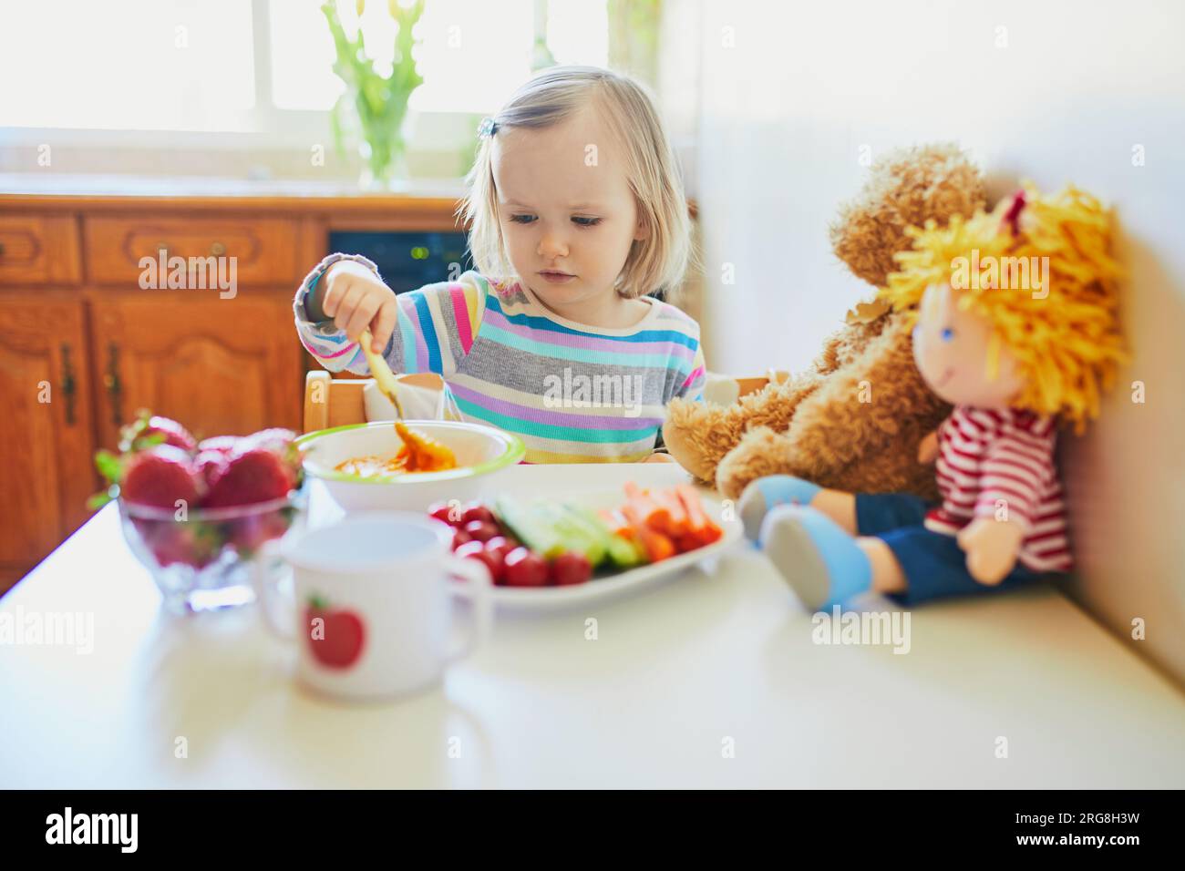 Adorable toddler girl eating fresh fruits and vegetables for lunch ...