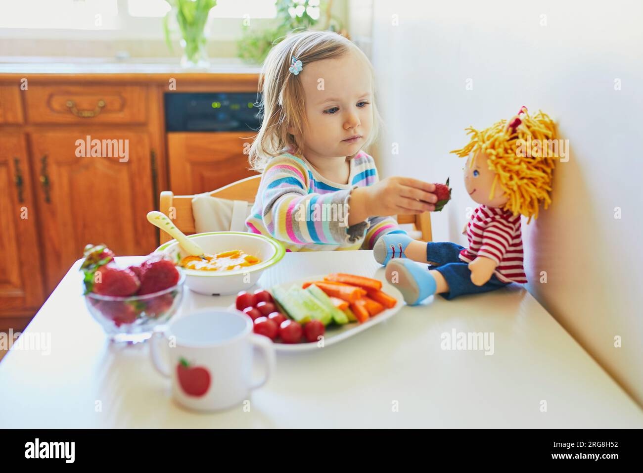 Adorable toddler girl eating fresh fruits and vegetables for lunch ...