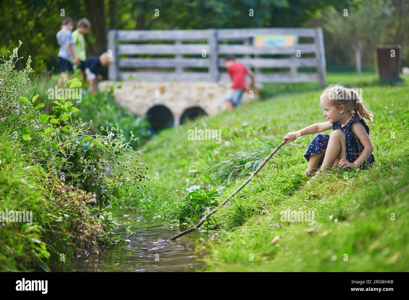 Preschooler girl playing with a twig like with fishing rod. Role games ...