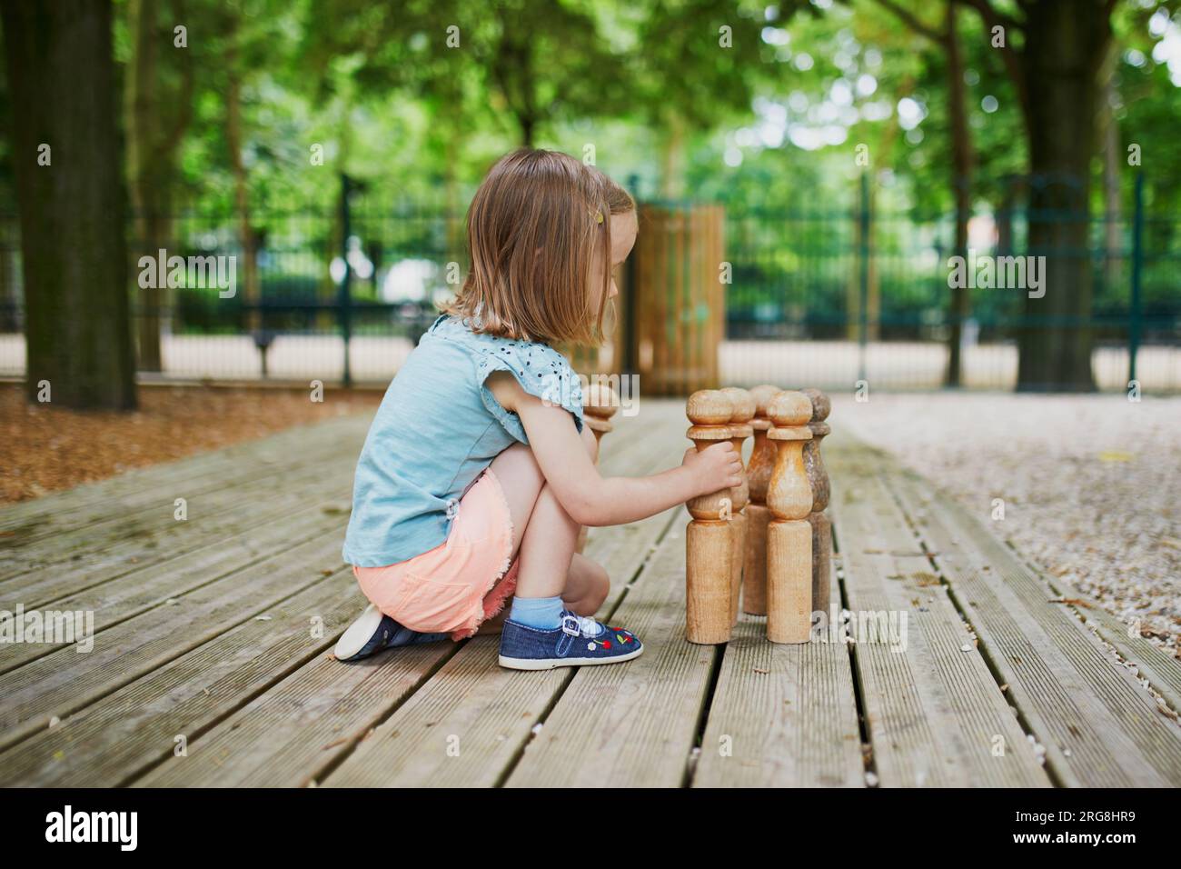 Adorable little girl on playground with bowls on a sunny day ...