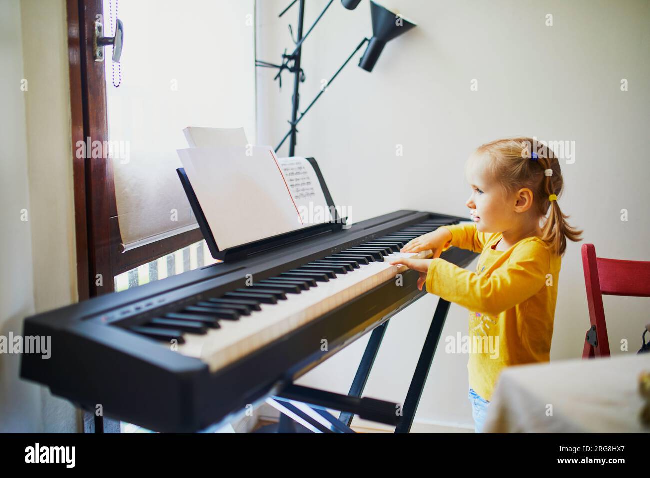 Adorable little girl playing piano. Preschooler child having fun while ...
