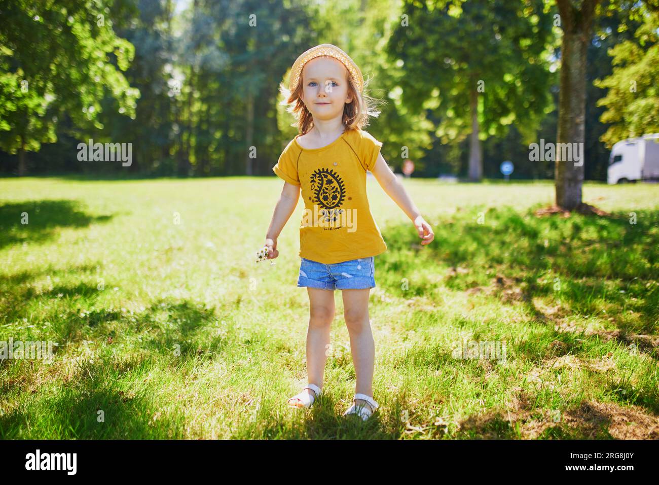 Happy cheerful toddler girl walking in park. Outdoors summer activities ...