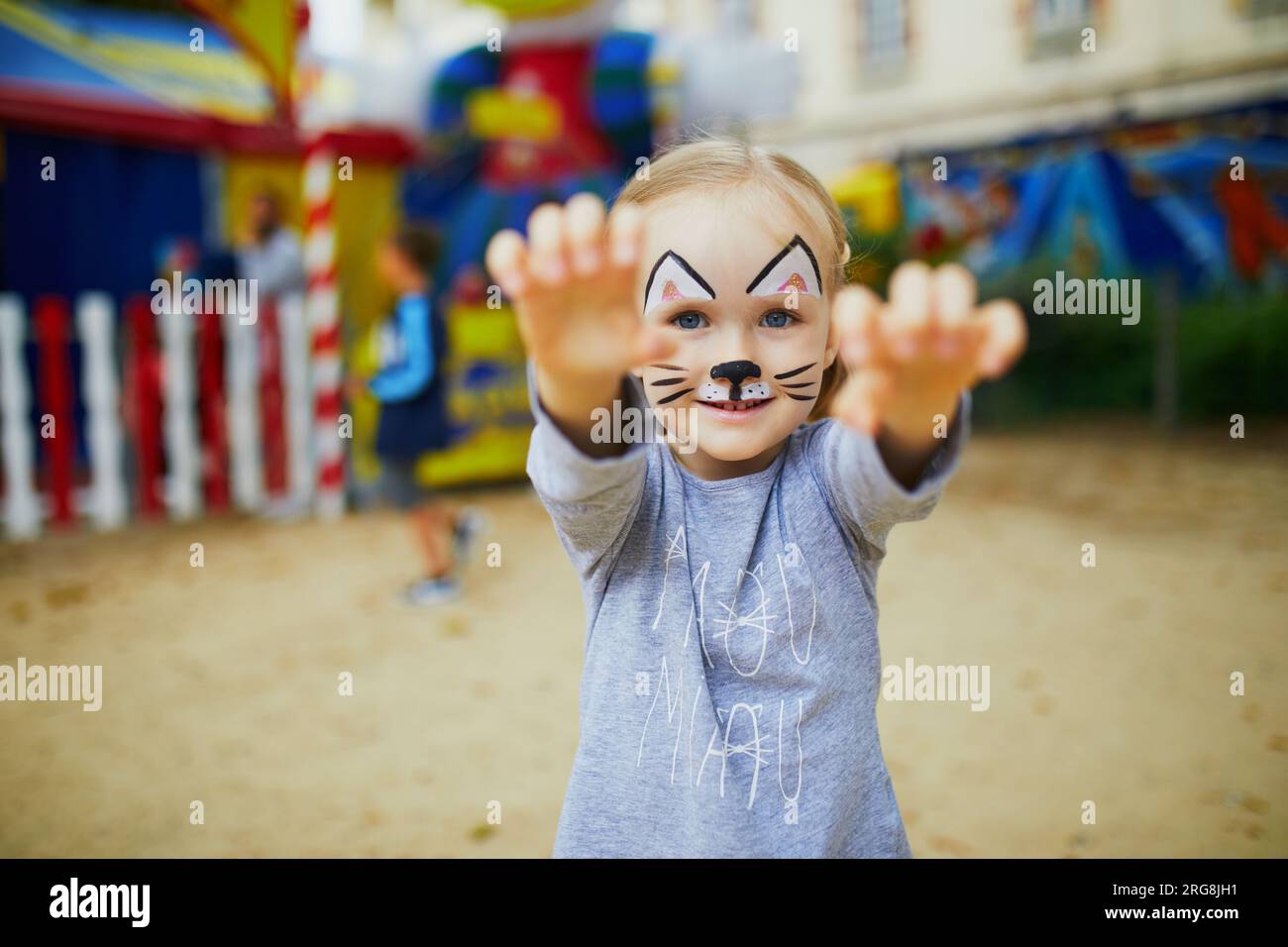 Little preschooler girl with cat face painting, making funny grimace ...
