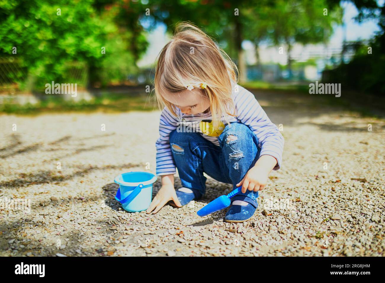 Adorable toddler girl playing with bucket and shovel, making mudpies ...