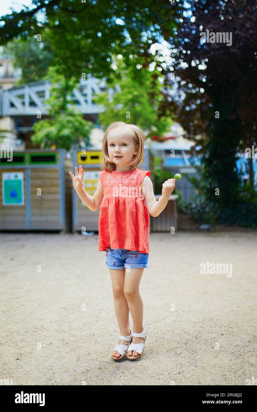 Adorable preschooler girl playing in park on a summer day. Happy child ...
