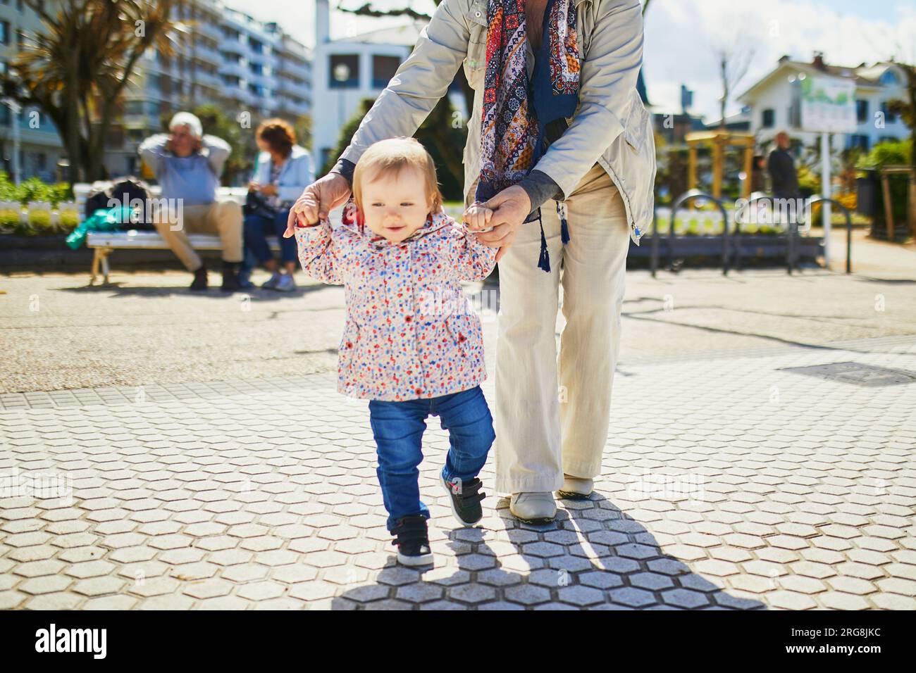 Grandmother helping granddaughter make her firts steps. Middle aged ...