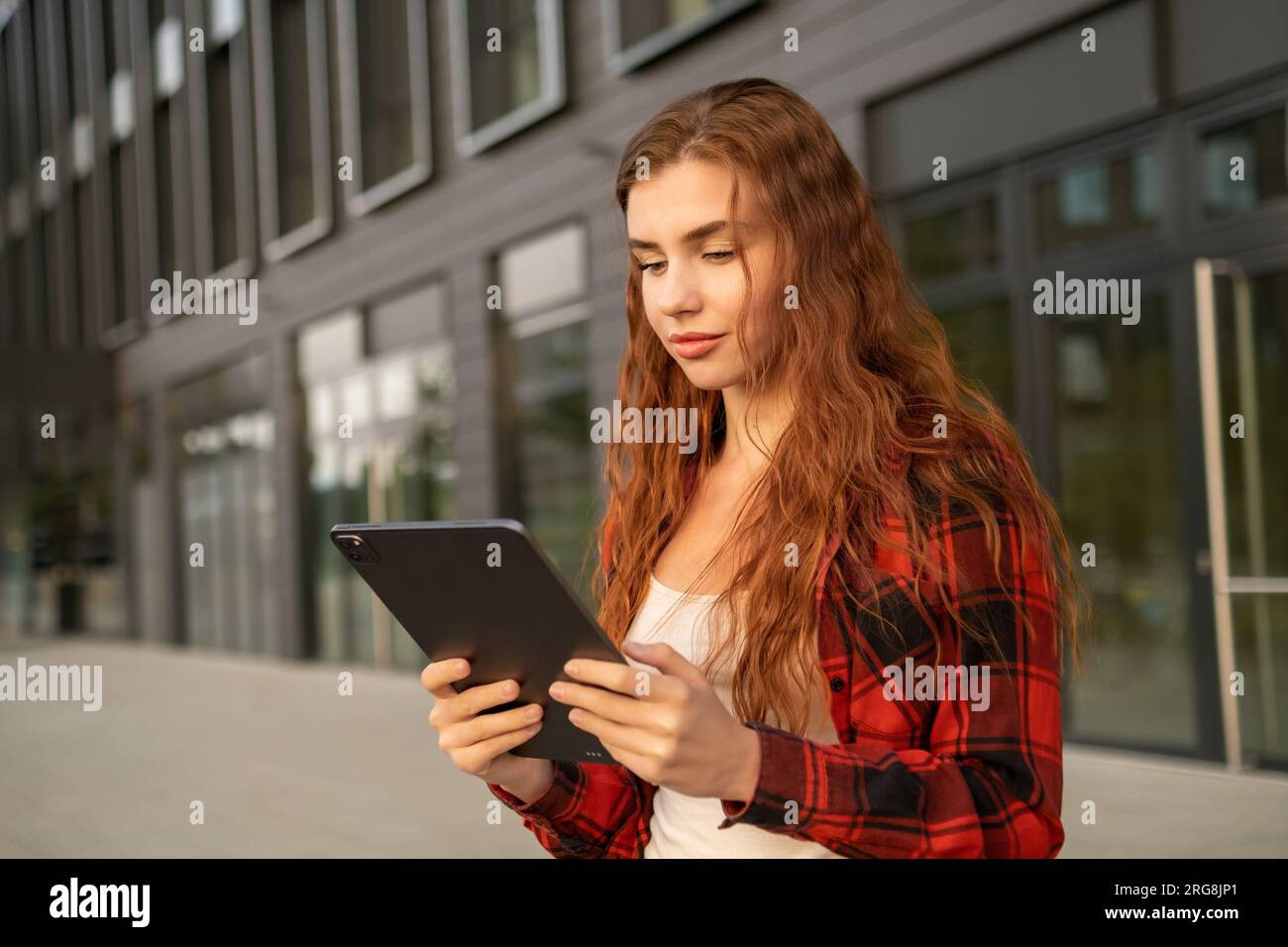 Female student holding a tablet standing near the business center ...