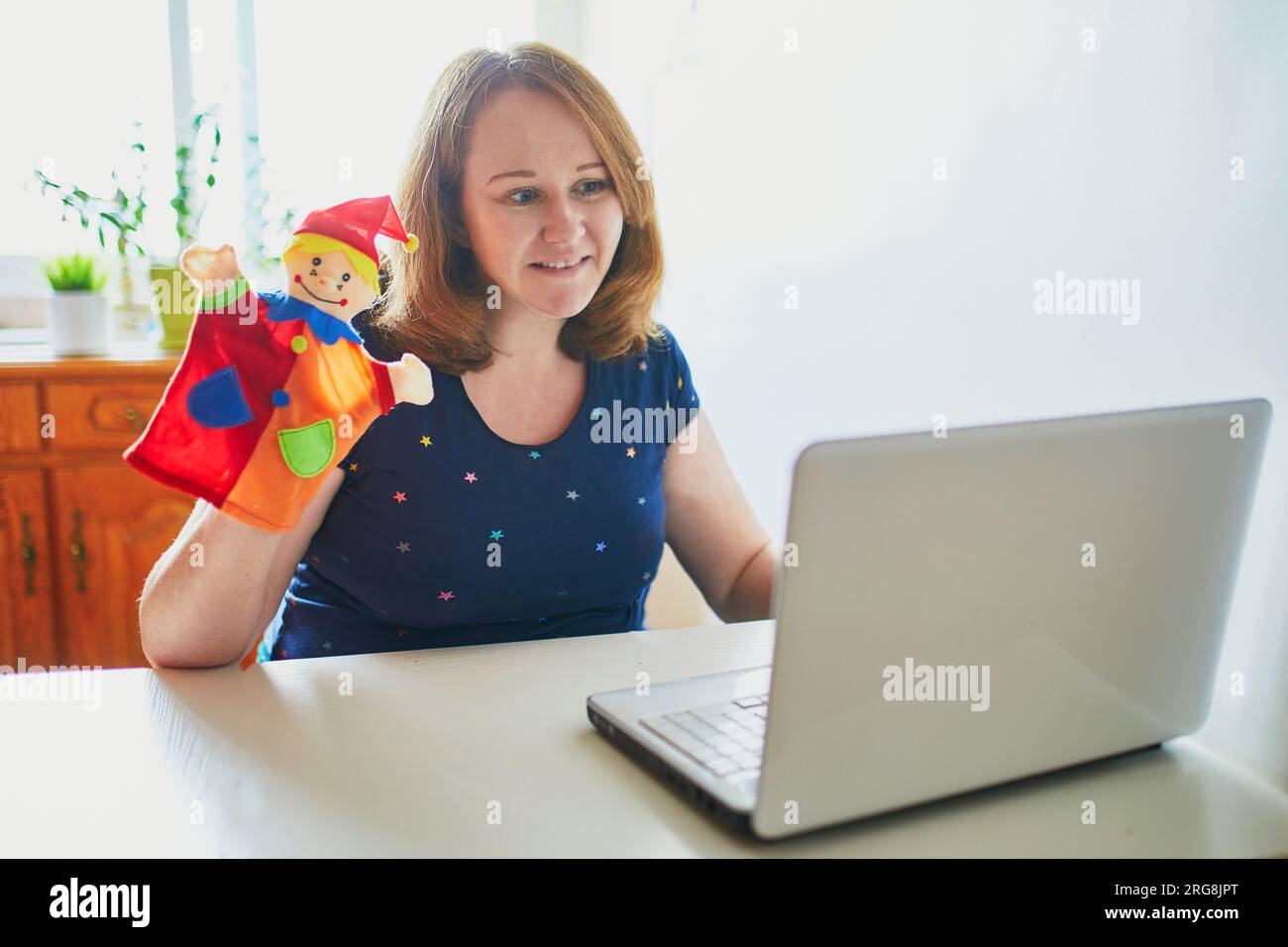Kindergarten teacher in front of laptop having video conference chat ...