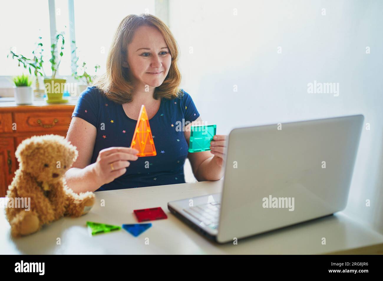 Kindergarten teacher in front of laptop having video conference chat ...