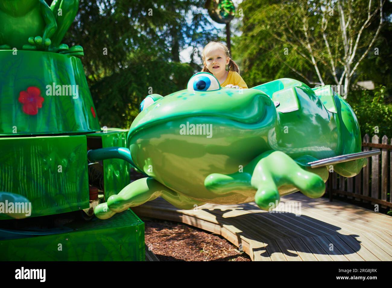Adorable little girl having fun in amusement park and taking a ride on ...