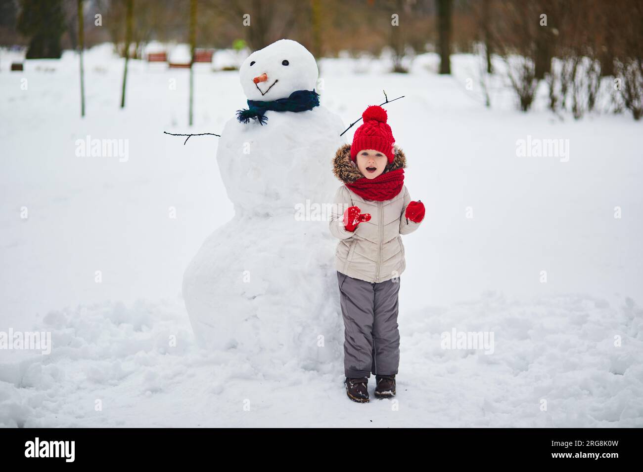 Adorable preschooler girl building a snowman on a day with heavy ...