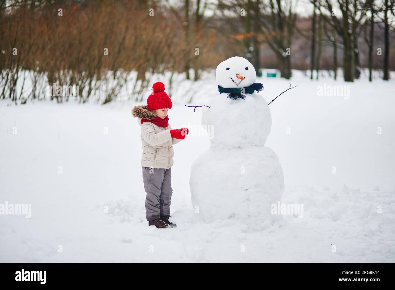 Adorable preschooler girl building a snowman on a day with heavy ...