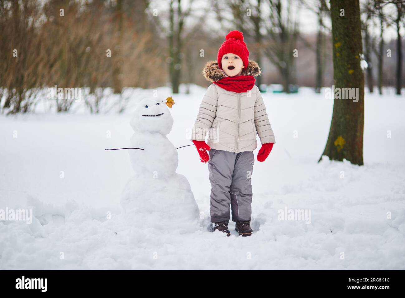 Adorable preschooler girl building a snowman on a day with heavy ...