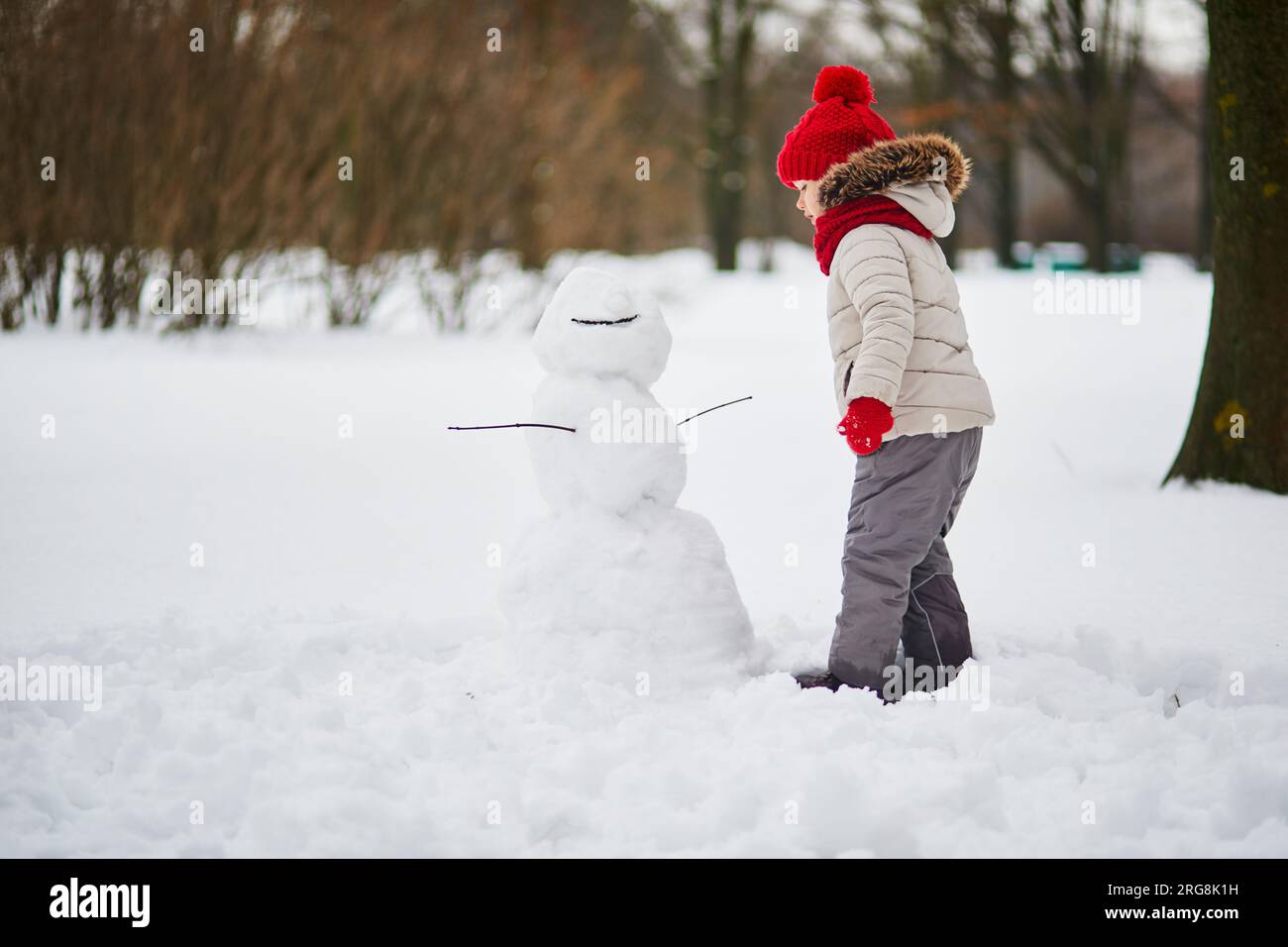 Adorable preschooler girl building a snowman on a day with heavy ...
