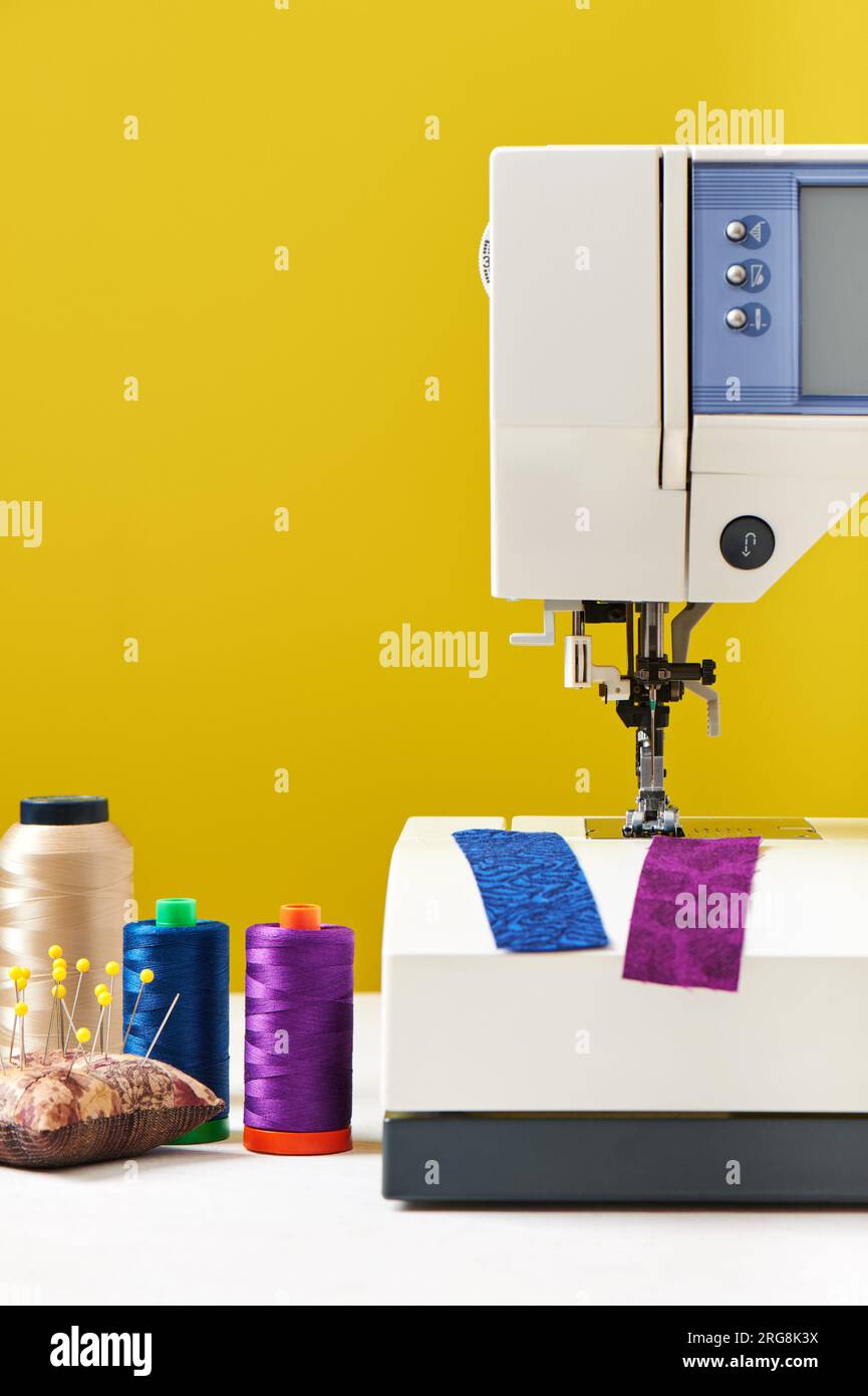 Spools of threads next to sewing machine on yellow background Stock ...