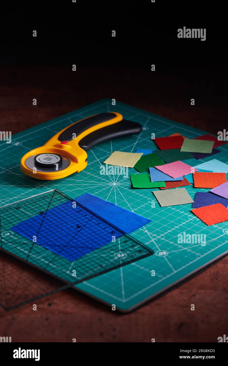 Heap square pieces of colorful fabrics, rotary cutter and ruler on ...