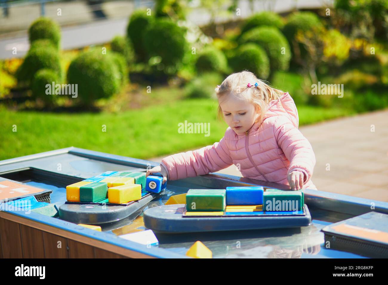 Little girl playing with toy water dam experimenting with balance wan ...