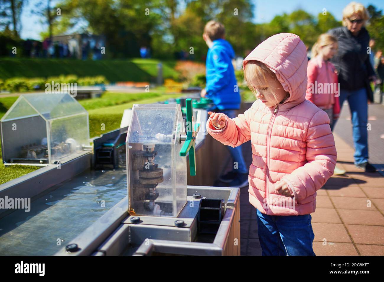 Little girl playing with toy water dam experimenting with balance wan ...