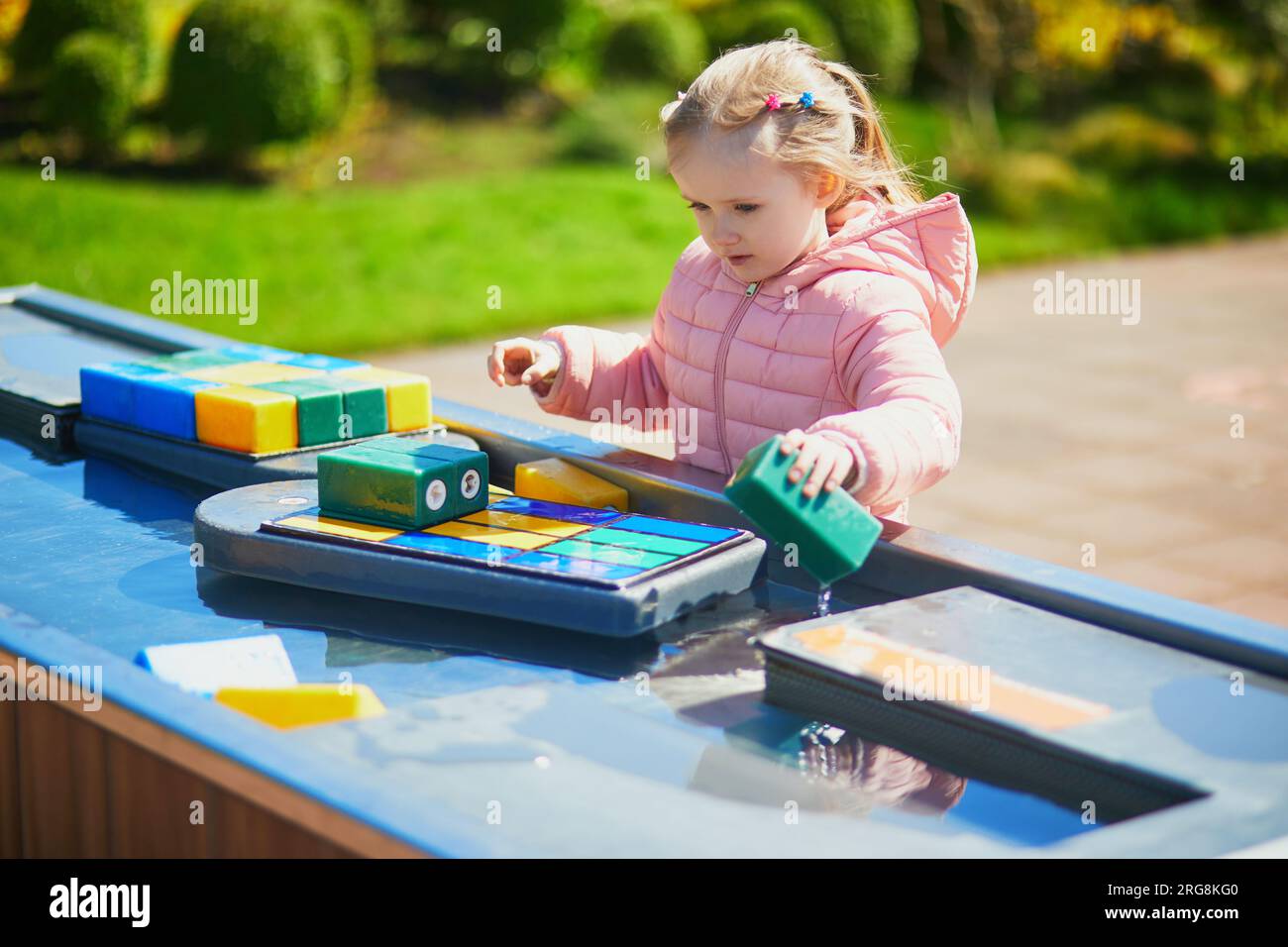 Little girl playing with toy water dam experimenting with balance wan ...