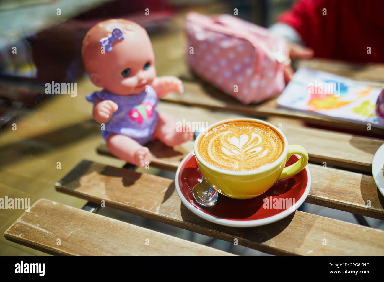 Adorable preschooler girl drawing in cafe while her mother is drinking ...