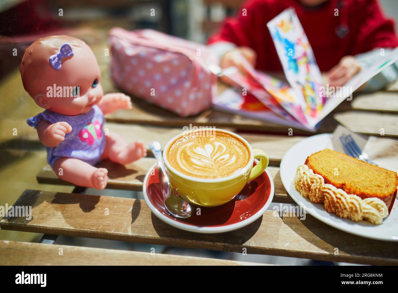 Adorable preschooler girl drawing in cafe while her mother is drinking ...