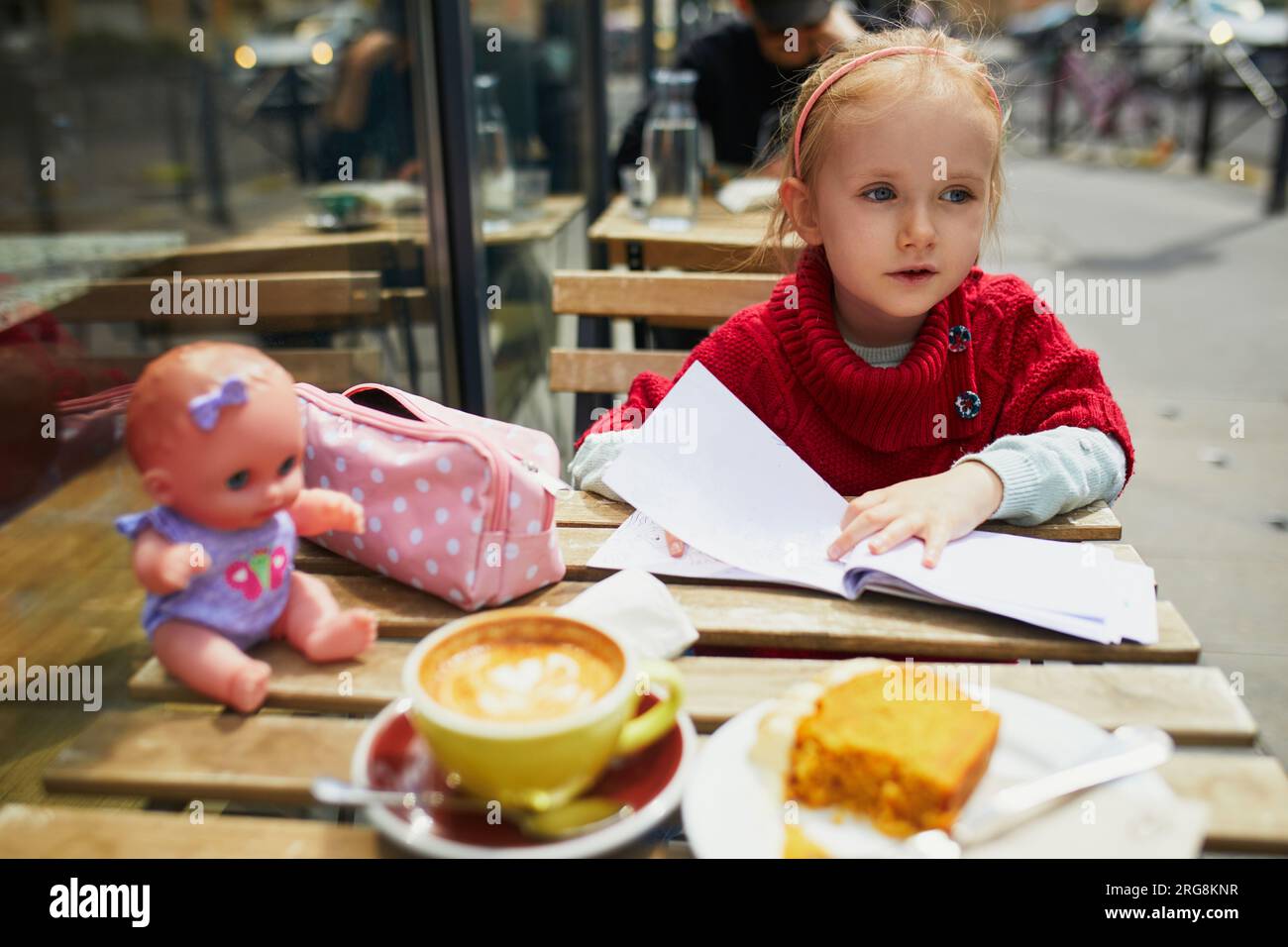 Adorable preschooler girl drawing in cafe while her mother is drinking ...