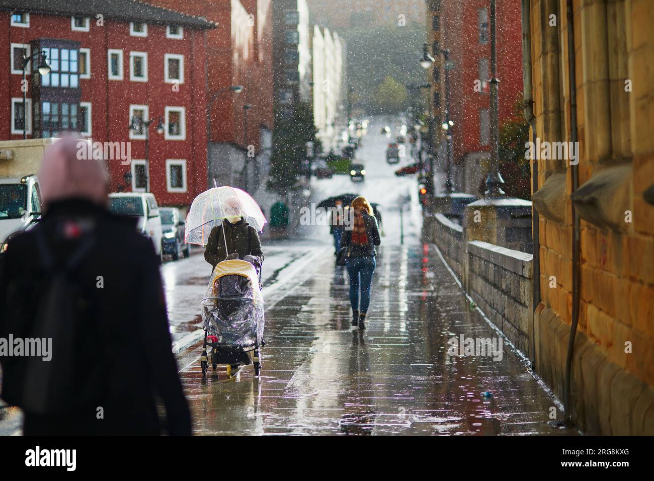 People walking under the rain on a street of Bilbao, Basque Country ...