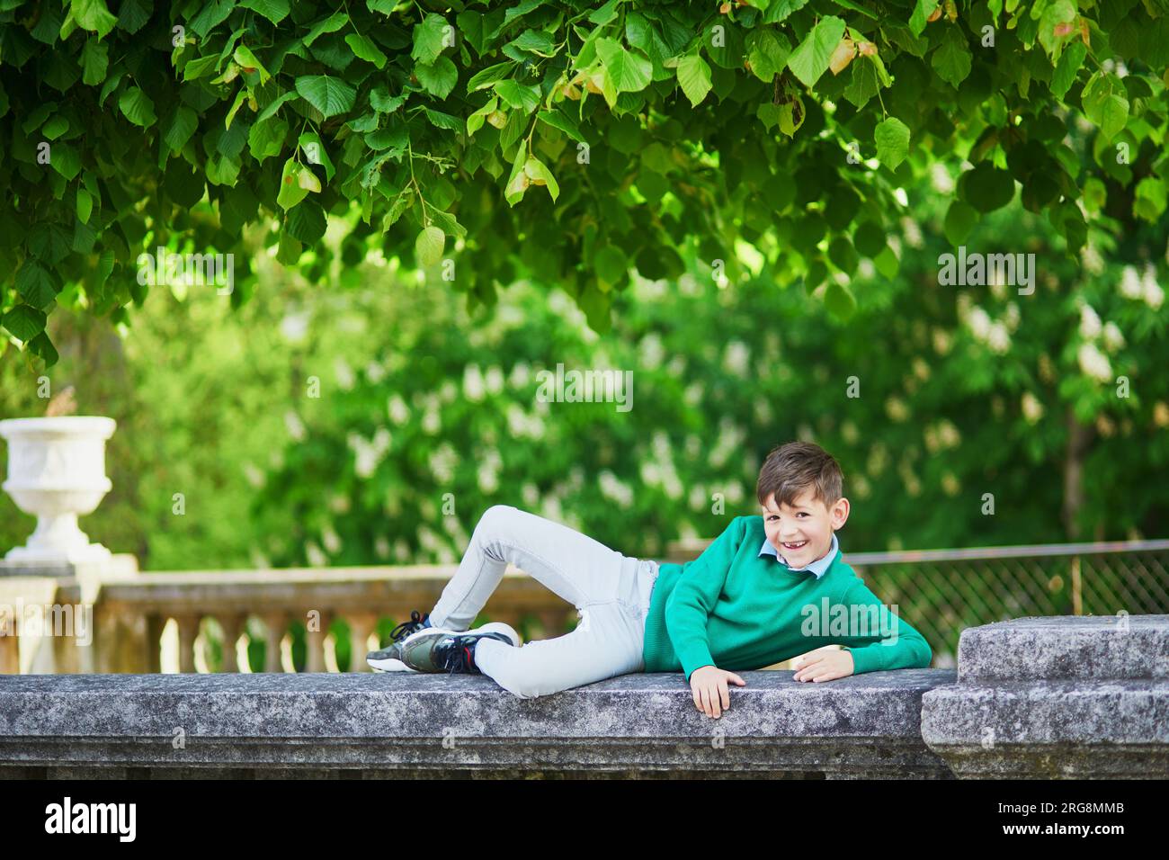 Eight year old boy with chestnuts in bloom in Tuileries garden in Paris ...