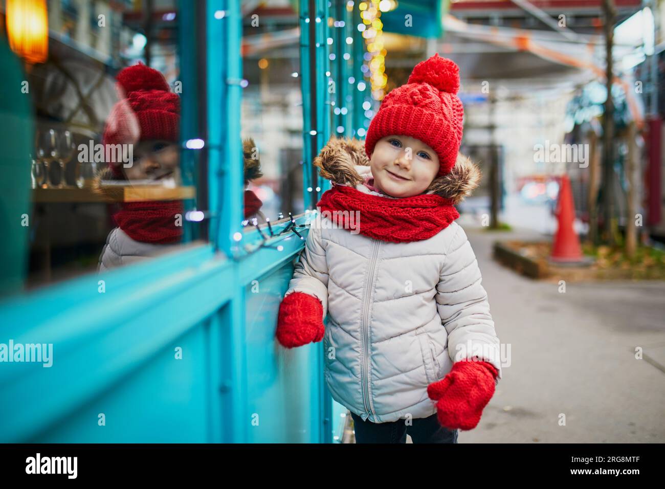 Preschooler girl looking at window glass of large department store ...