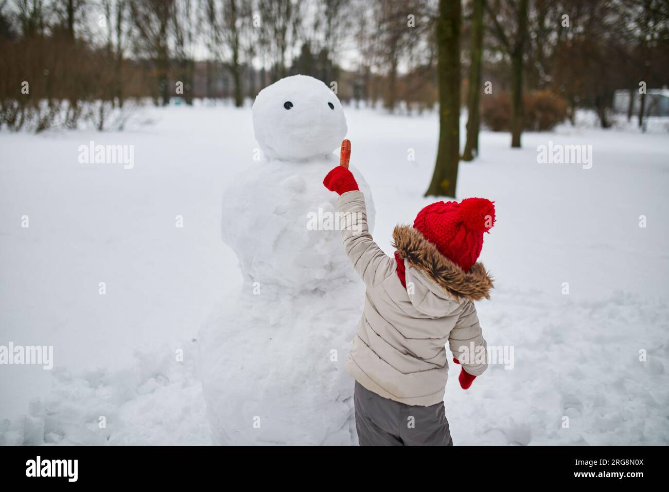 Adorable preschooler girl building a snowman on a day with heavy ...