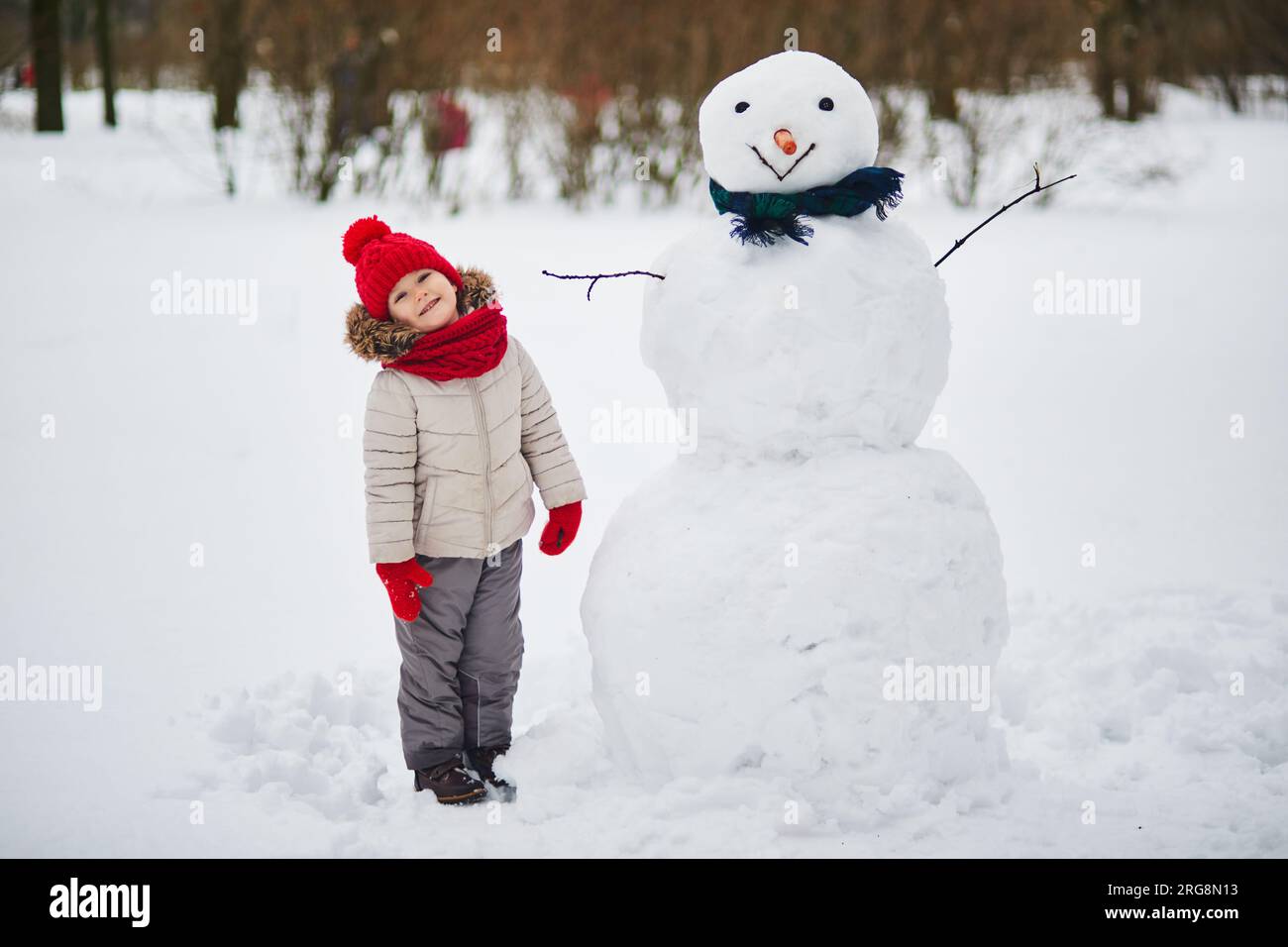 Adorable preschooler girl building a snowman on a day with heavy ...