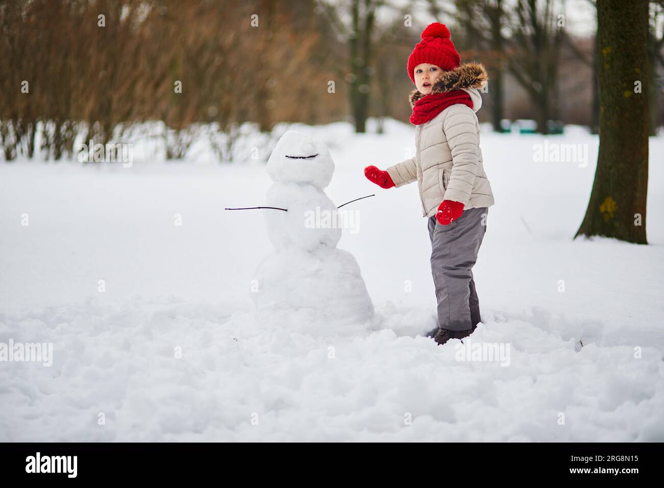 Adorable preschooler girl building a snowman on a day with heavy ...