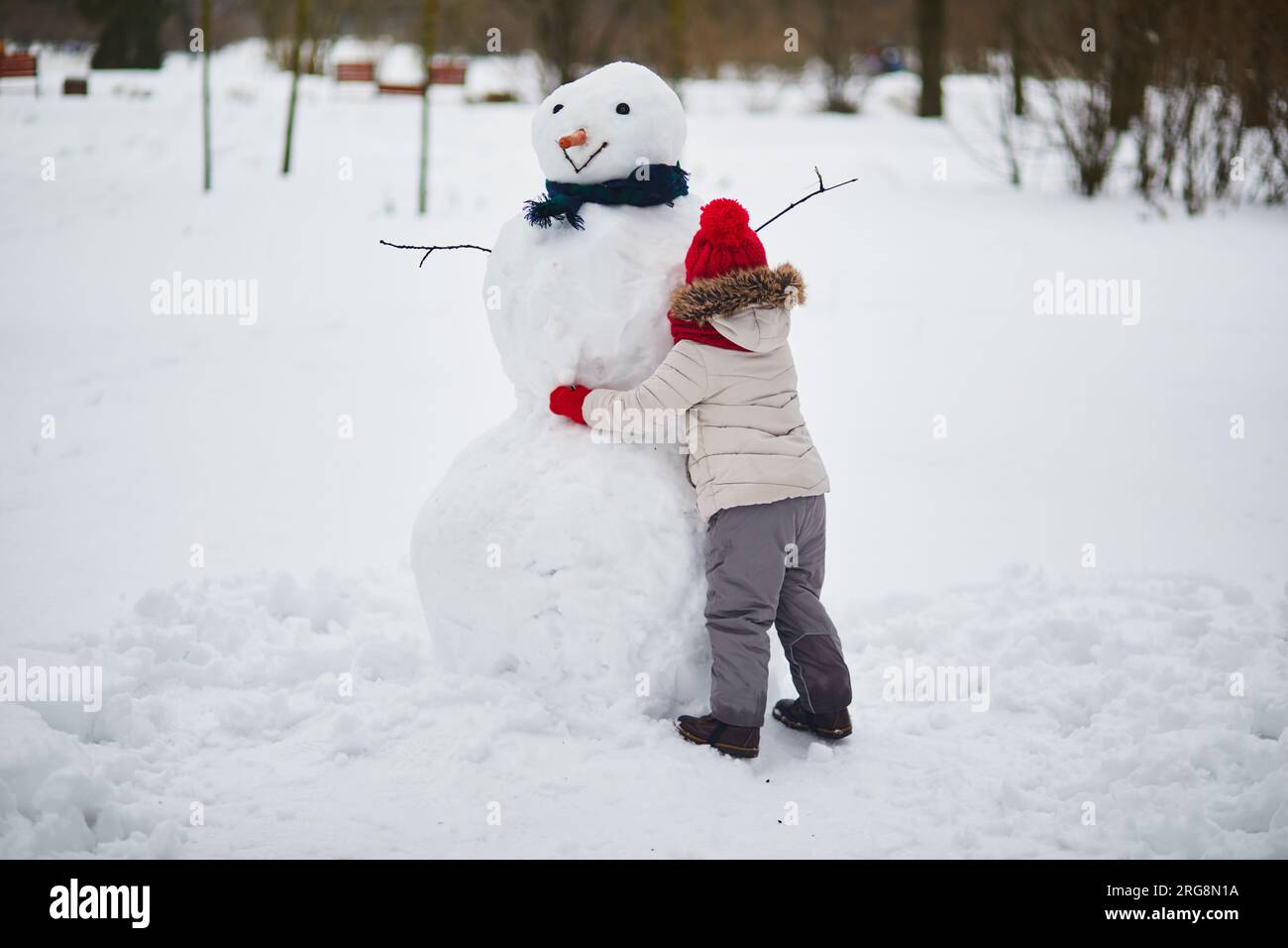 Adorable preschooler girl building a snowman on a day with heavy ...