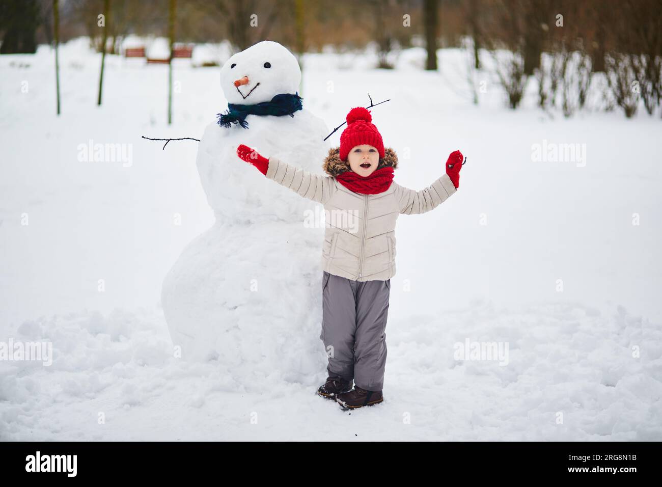 Adorable preschooler girl building a snowman on a day with heavy ...