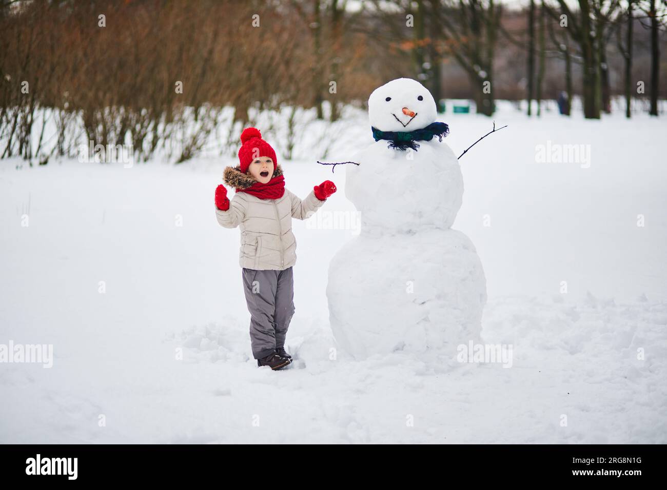 Adorable preschooler girl building a snowman on a day with heavy ...