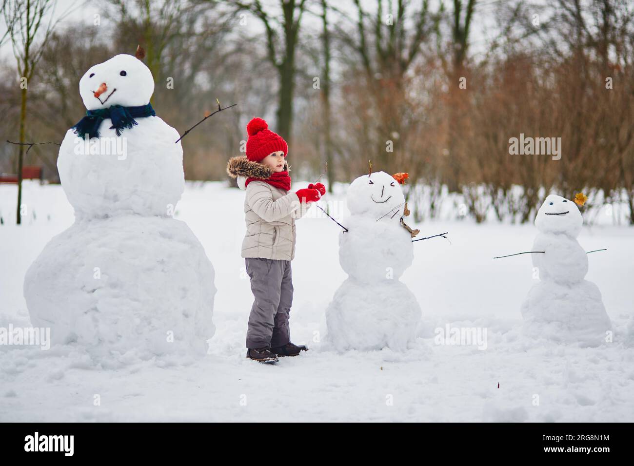 Adorable preschooler girl building a snowman on a day with heavy ...
