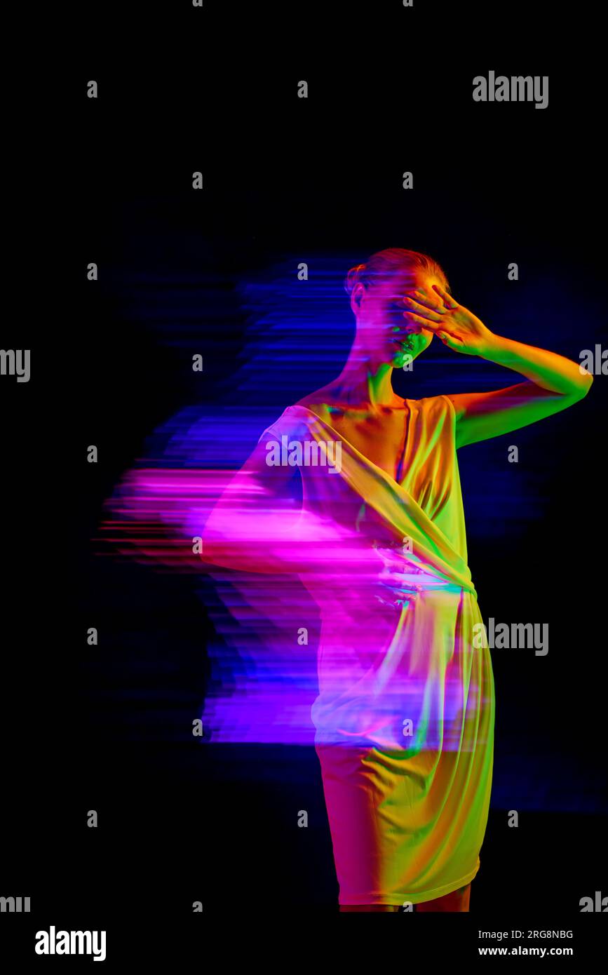 Image of woman in white midi dress posing in bright colorful neon light ...